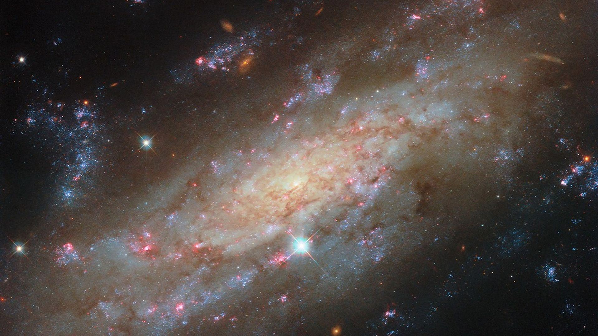 Clusters of bright blue stars and glowing red gas clouds steal the show ...